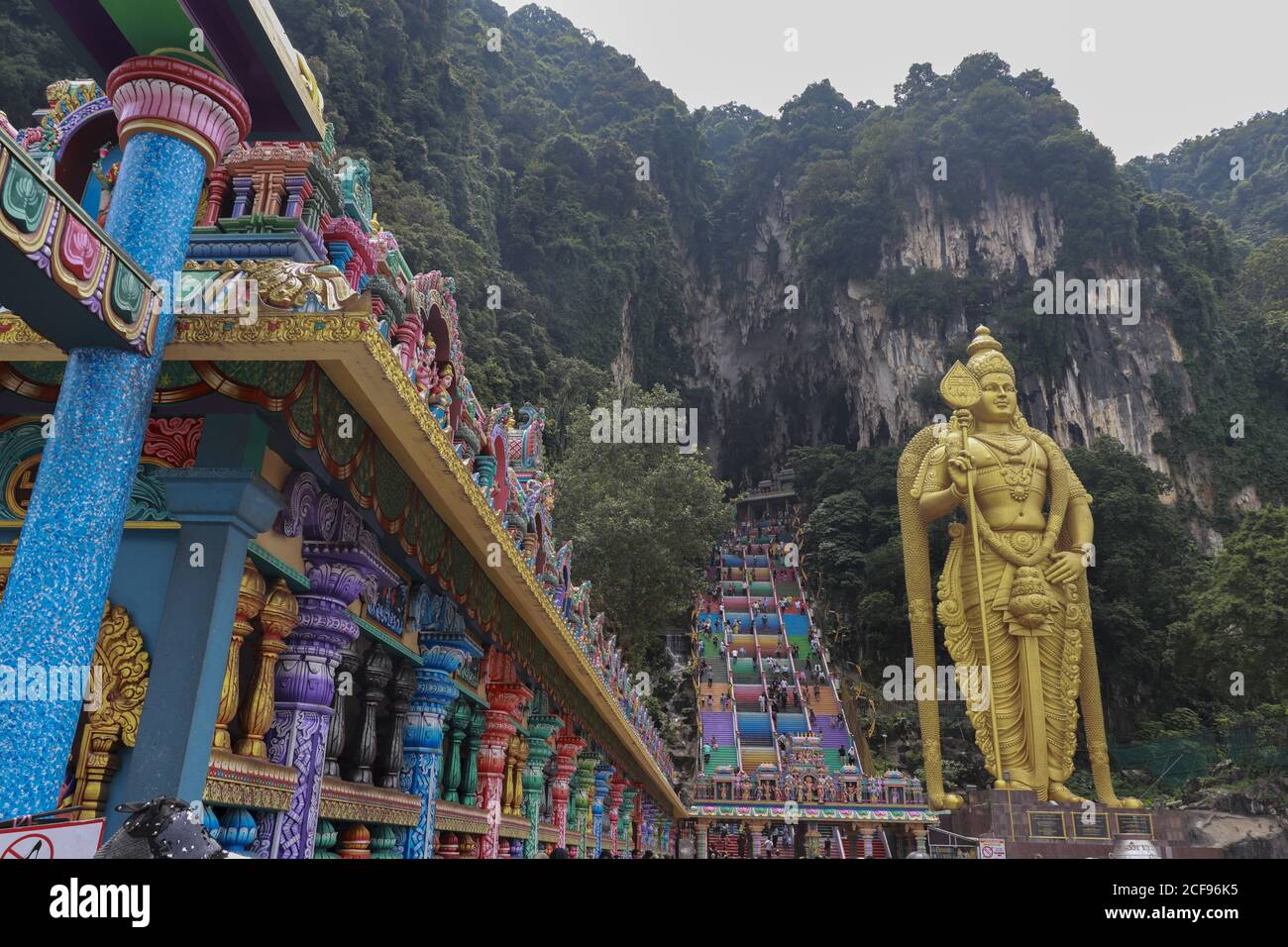 Low angle shot of the colorful Batu Caves and the gold Buddha sculpture ...