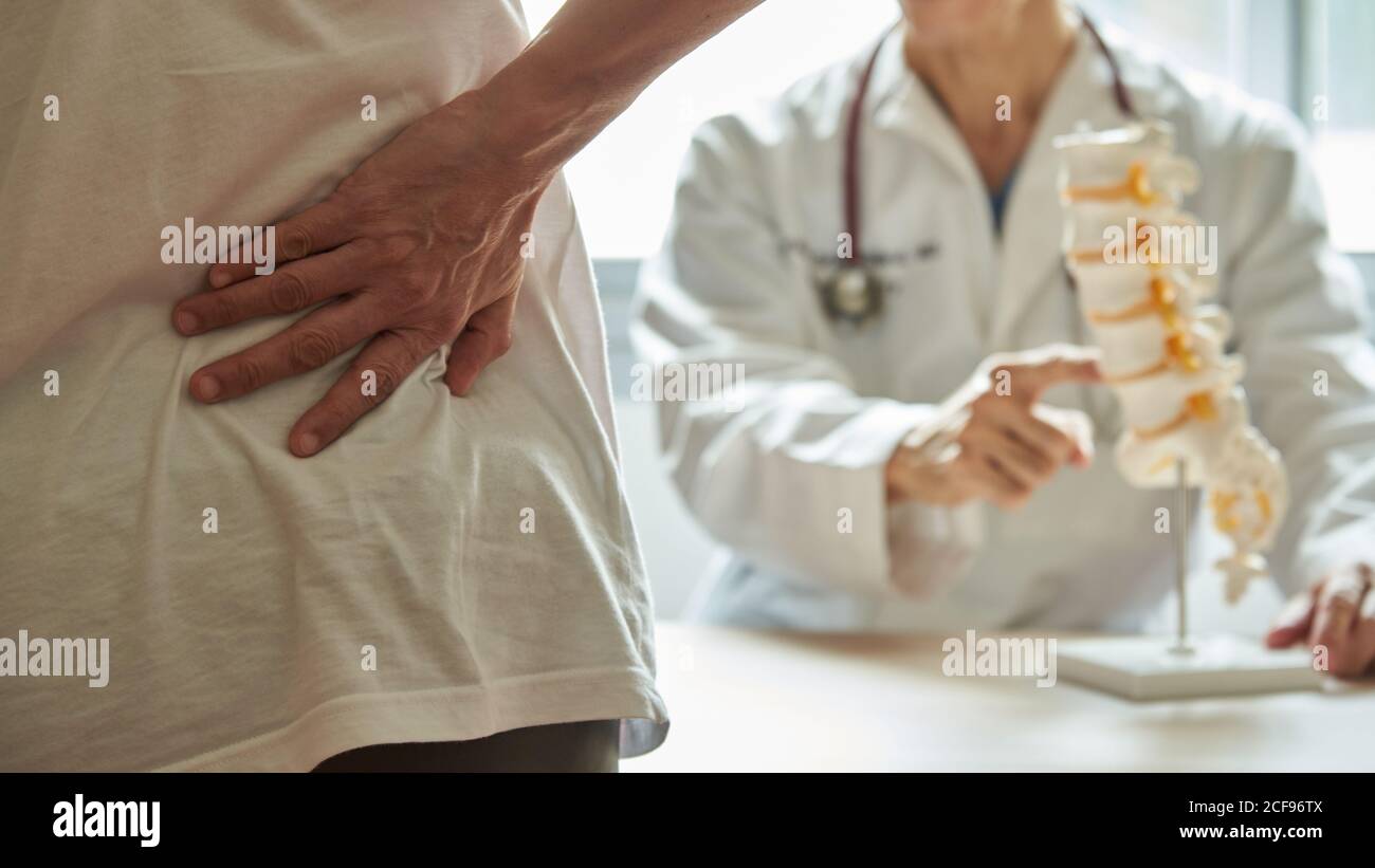 A male doctor explaining lumbar anatomy to female patient complaining ...