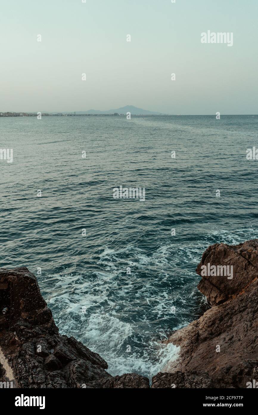 Aerial view of sea waves hitting rocky cliff with splash and foam on ...