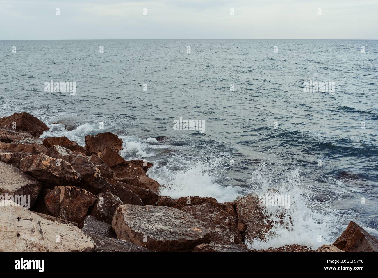 Aerial view of sea waves hitting rocky cliff with splash and foam on ...