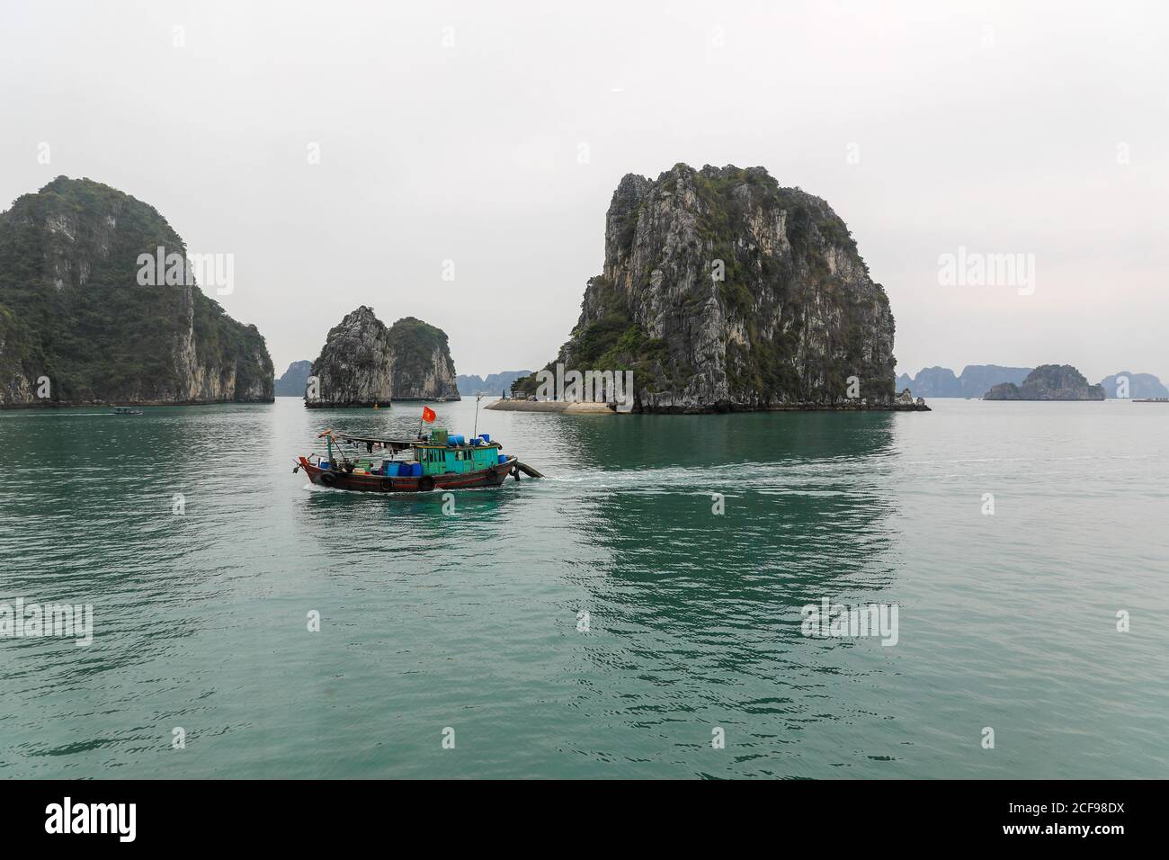 A fishing boat passing Cong Do Island, Bai Tu Long Bay, Halong Bay ...