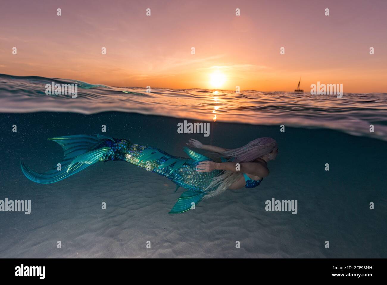 Side view of beautiful carefree young mermaid with shiny blue fishtail ...
