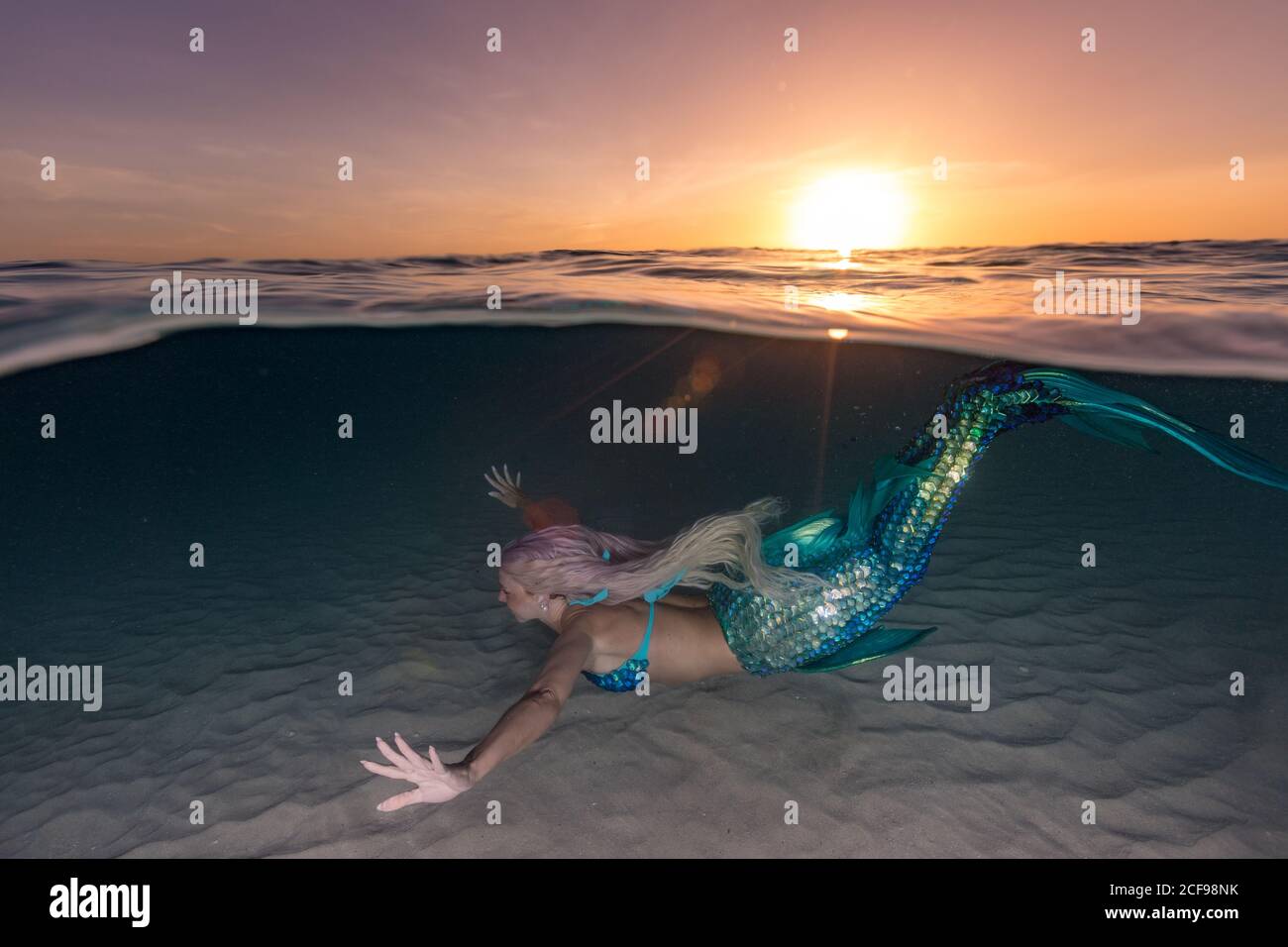 Side view of beautiful carefree young mermaid with shiny blue fishtail ...