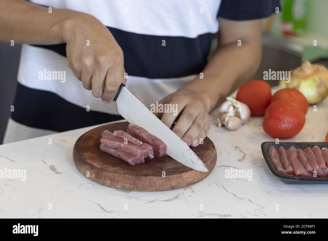 Closeup shot of a person slicing beef on a kitchen table with ...