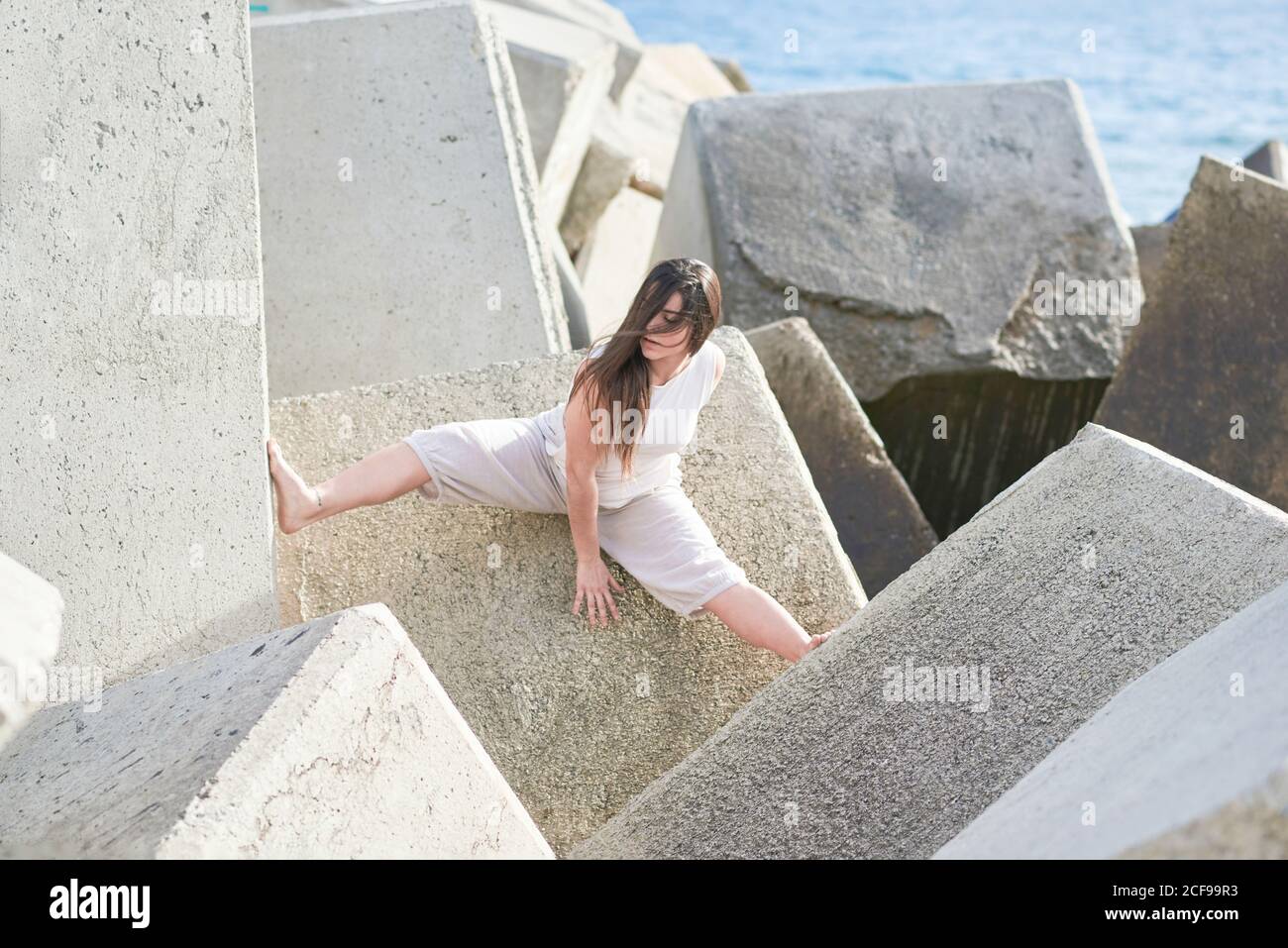 From above of young female in white clothes pushing legs against ...