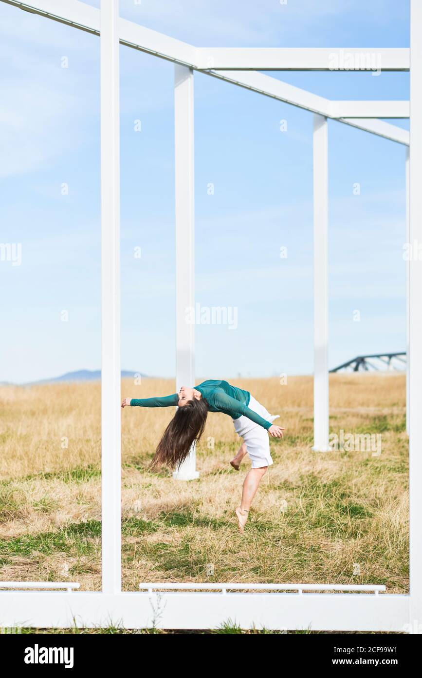 Back view of unrecognizable female bending back and falling down while ...