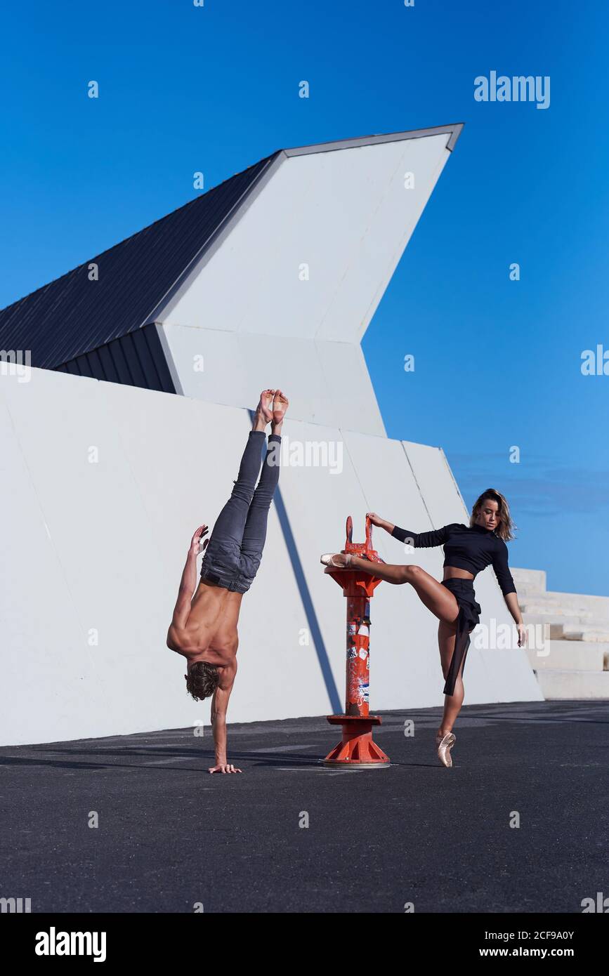 Upside down shirtless male acrobat in jeans doing handstand with one ...