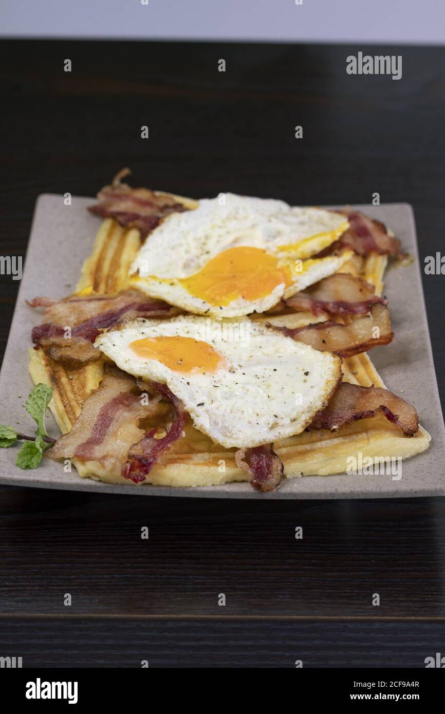 Vertical shot of a gourmet breakfast with waffles, eggs, and bacon ...