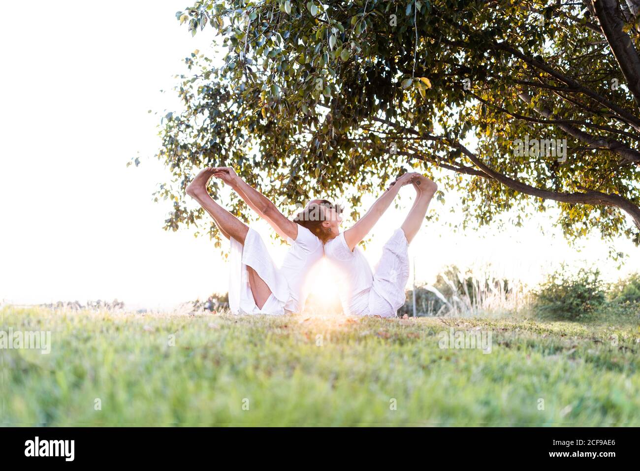 Side view of relaxed couple sitting in yoga position raising legs up ...