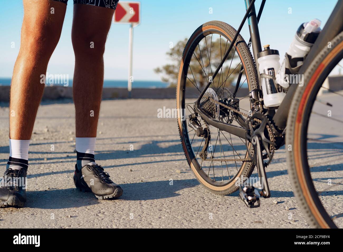 Cyclist man feet and bike wheel on coastal road Stock Photo - Alamy