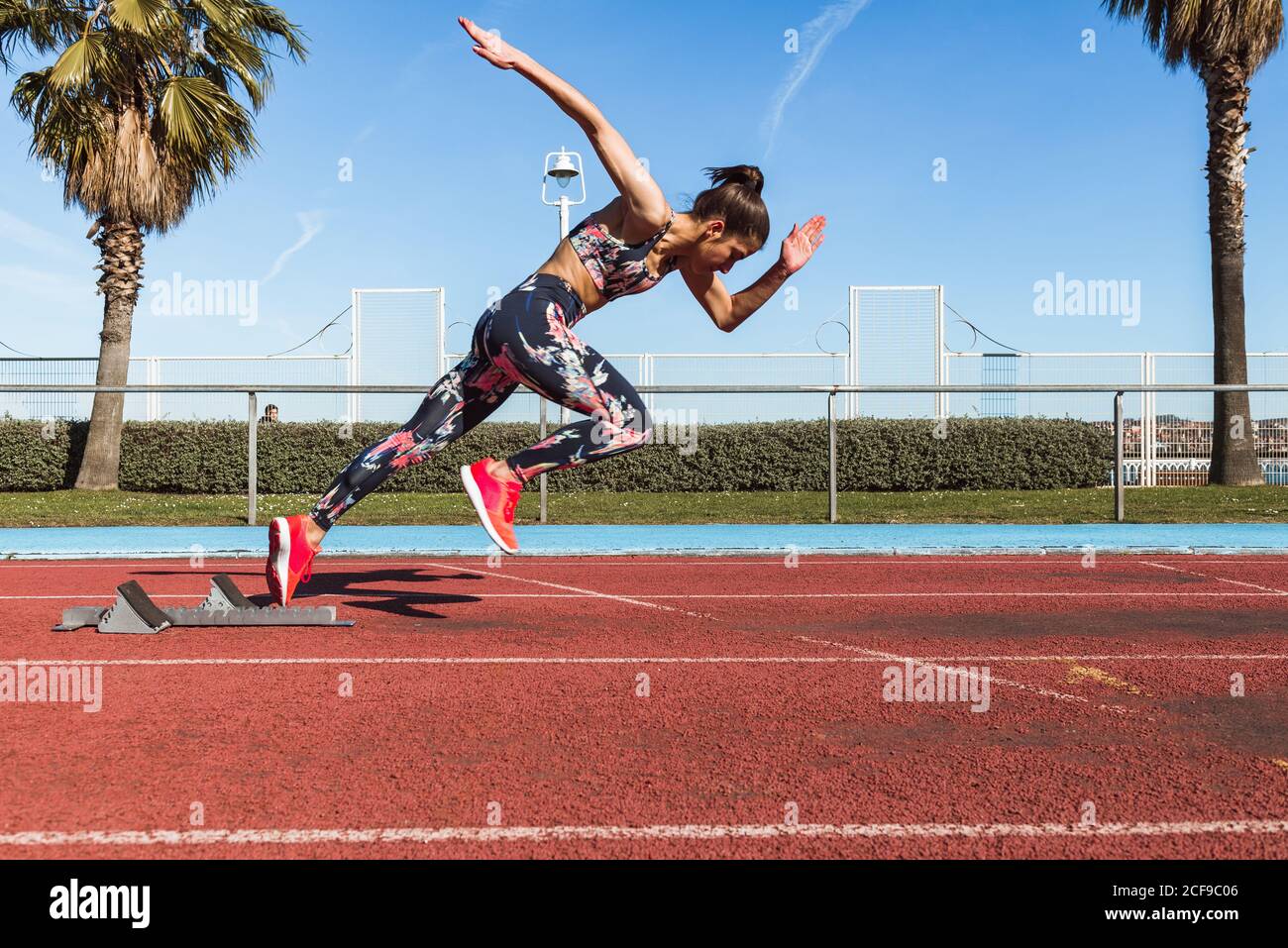 Side view of strong female athlete in sportswear running fast against ...