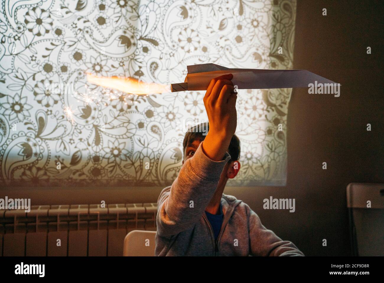 Amused boy playing with paper airplane with petard in room Stock Photo ...