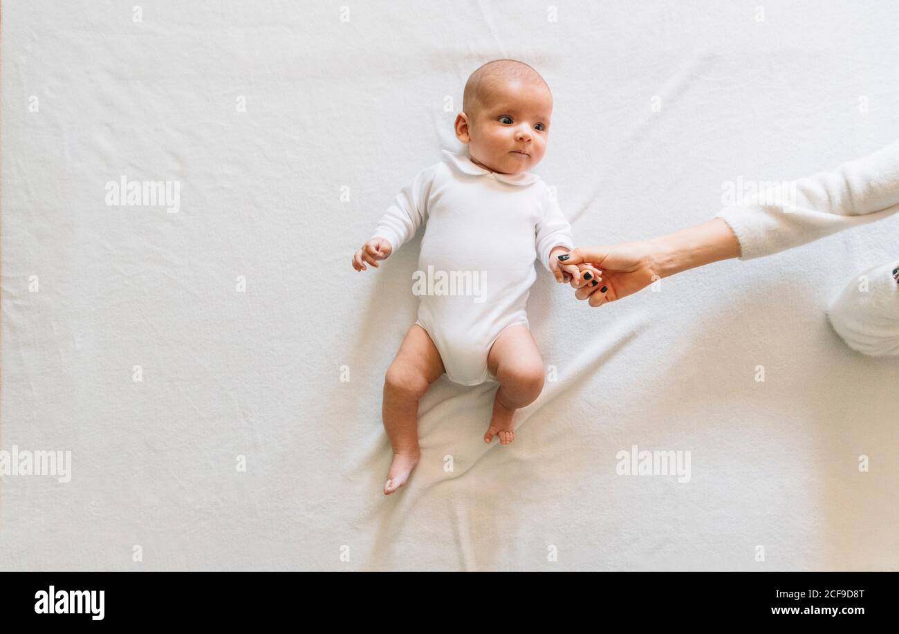 Top view of faceless Woman touching hands of joyful newborn infant with ...