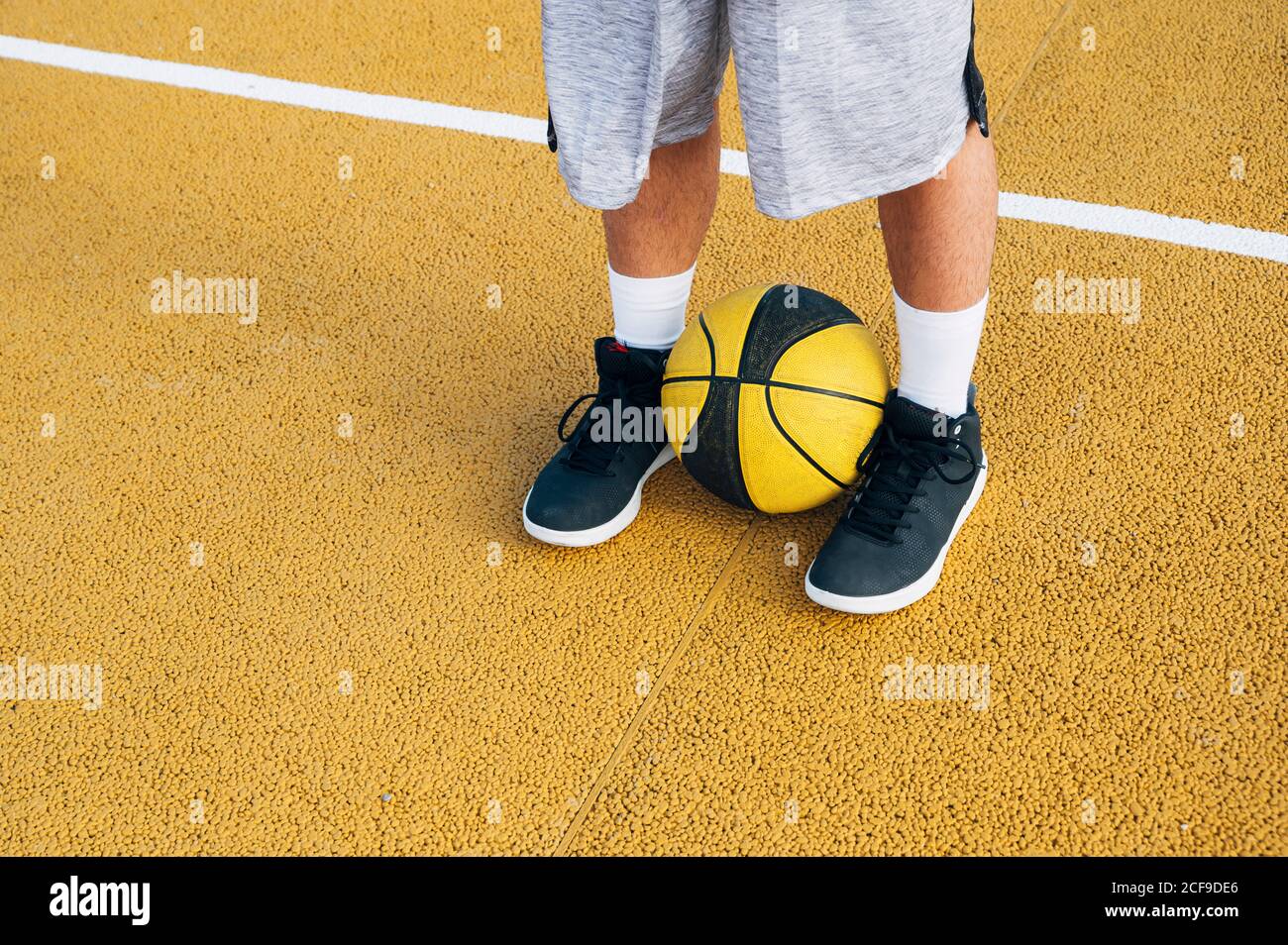 legs of crop Young man and ball playing on basketball court outdoor ...