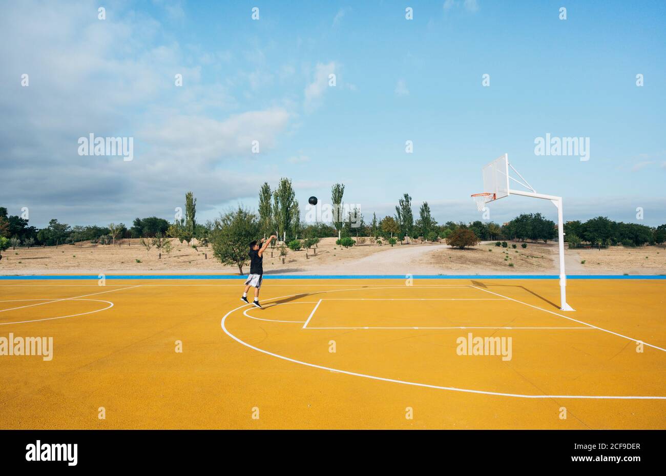 Young man playing on yellow basketball court outdoor Stock Photo - Alamy