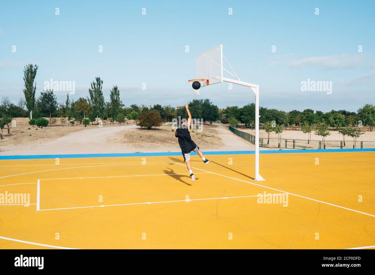 Young man playing on yellow basketball court outdoor Stock Photo - Alamy