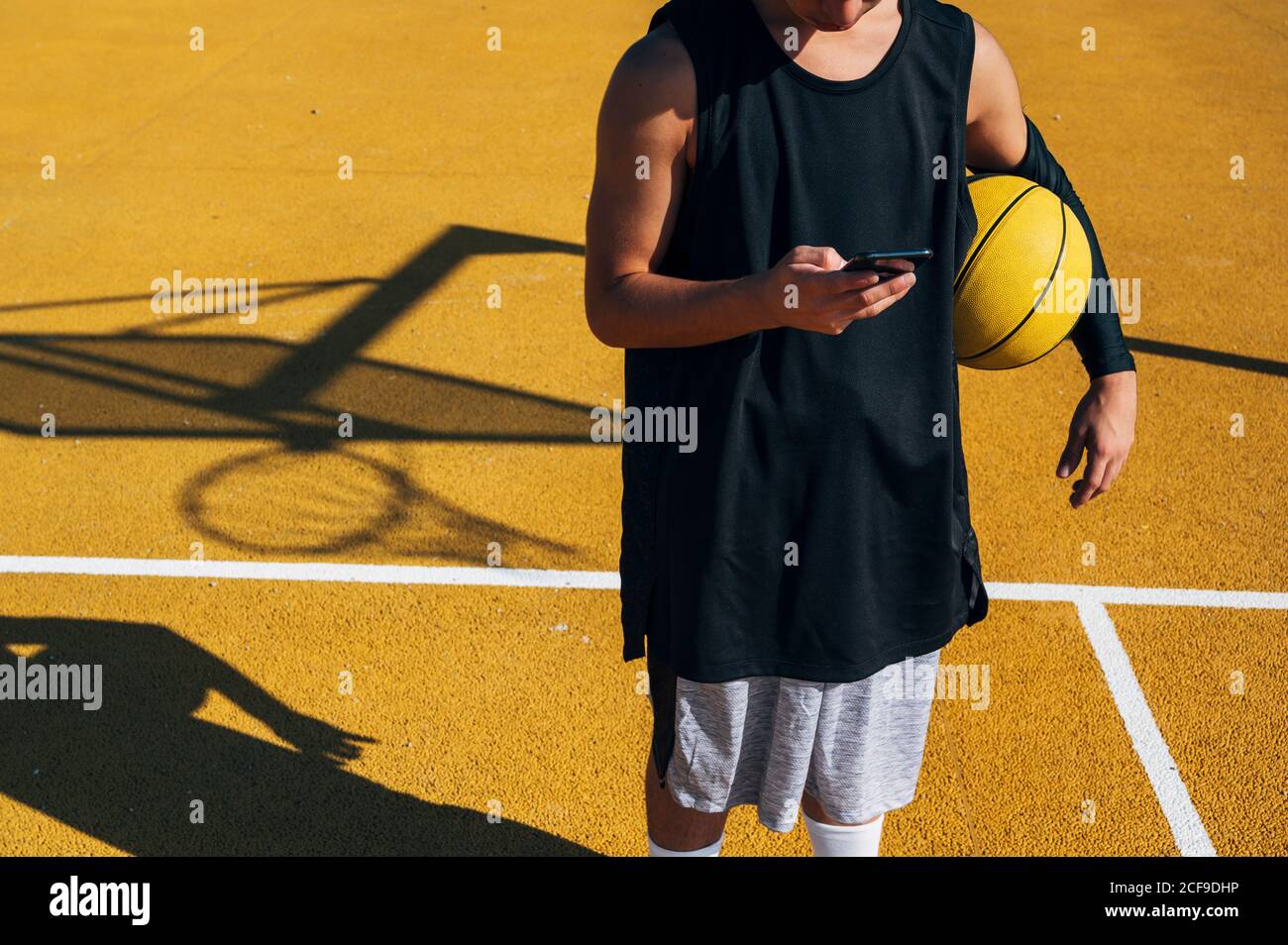 Male basketball player using his smartphone resting after training ...
