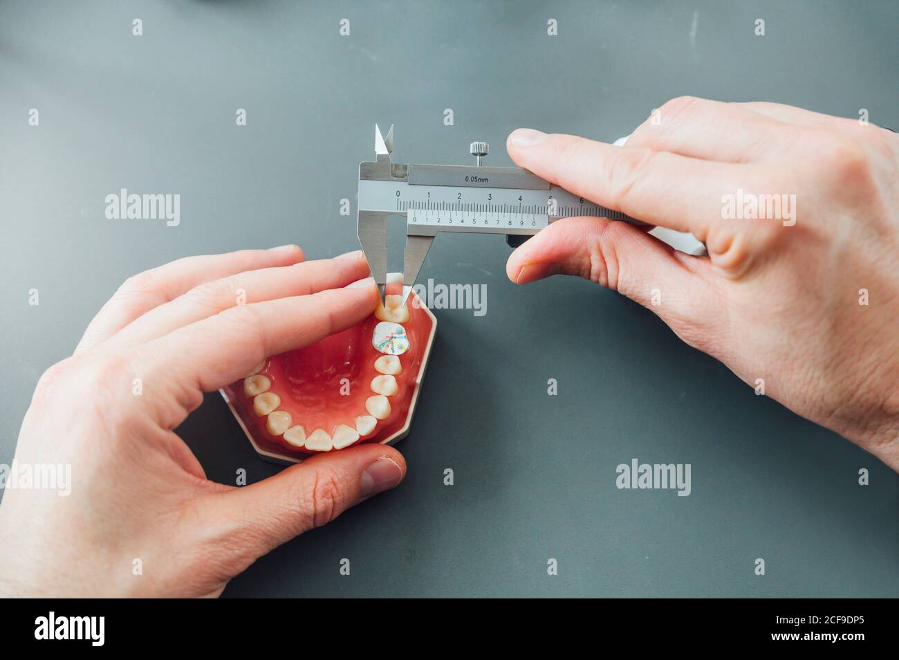 From above of crop male dentistry student using caliper for measuring ...