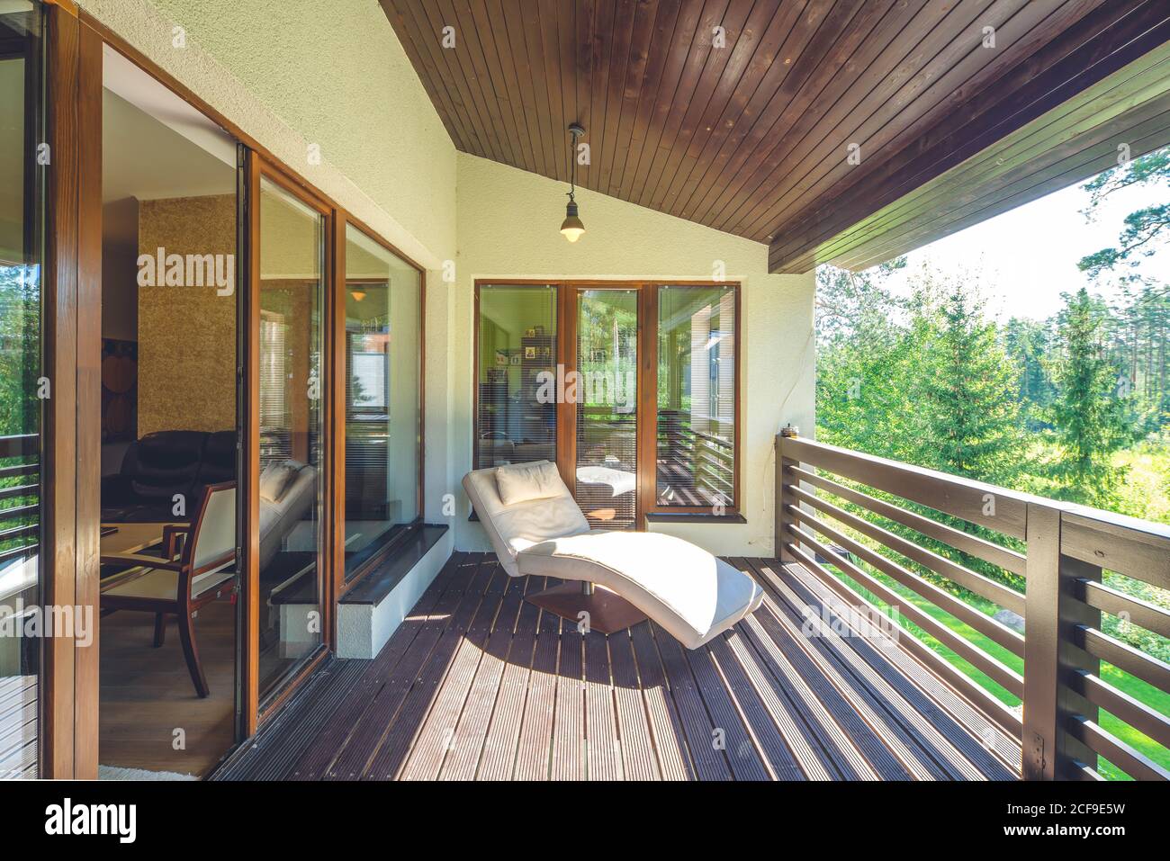 Cozy lounge chair on wooden terrace. Luxury cottage. Green forest at ...