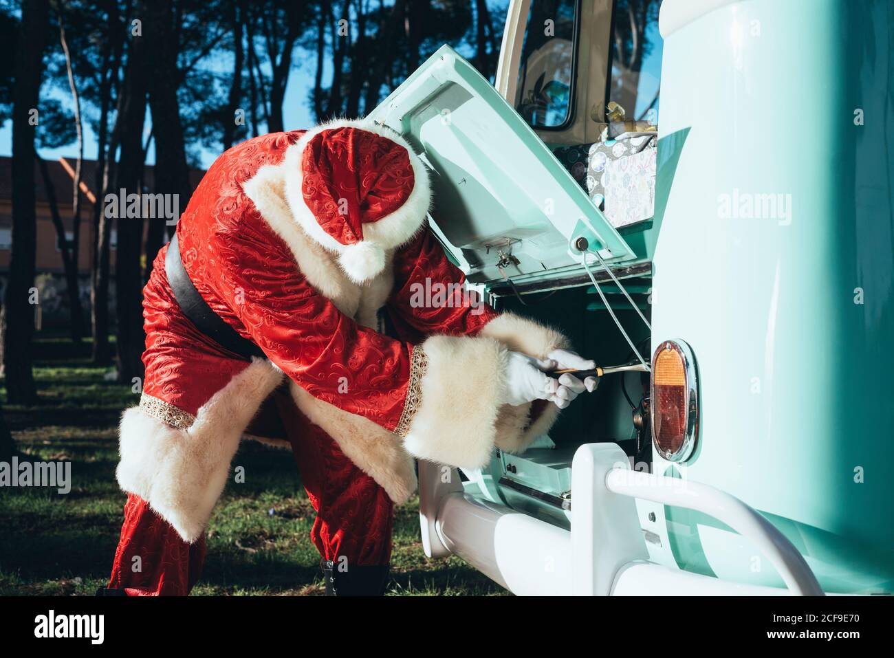 Person in red and white costume of Santa Claus inspecting engine of ...