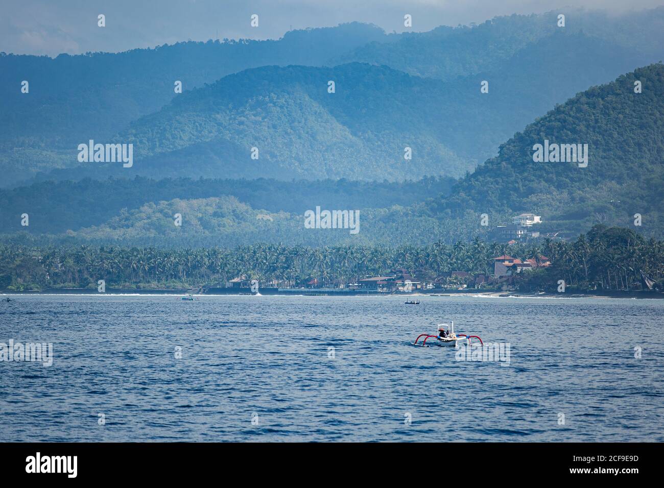 small boat floats on water with amazing mountain views. High quality ...