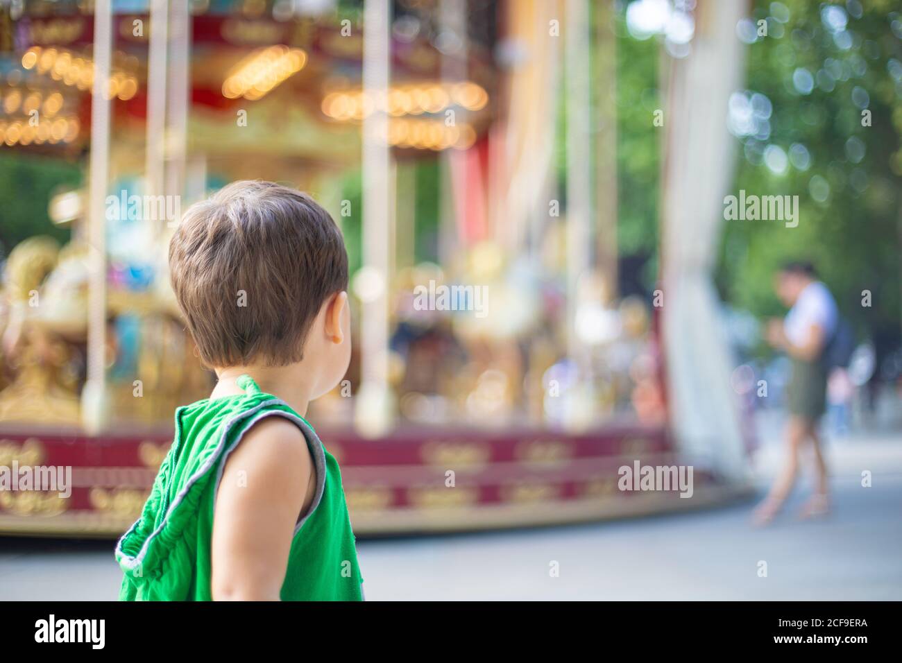 Child watching moving carousel and dreaming at fair Stock Photo - Alamy