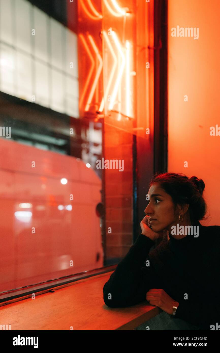 Side view of gorgeous young ethnic Woman looking out window with red ...
