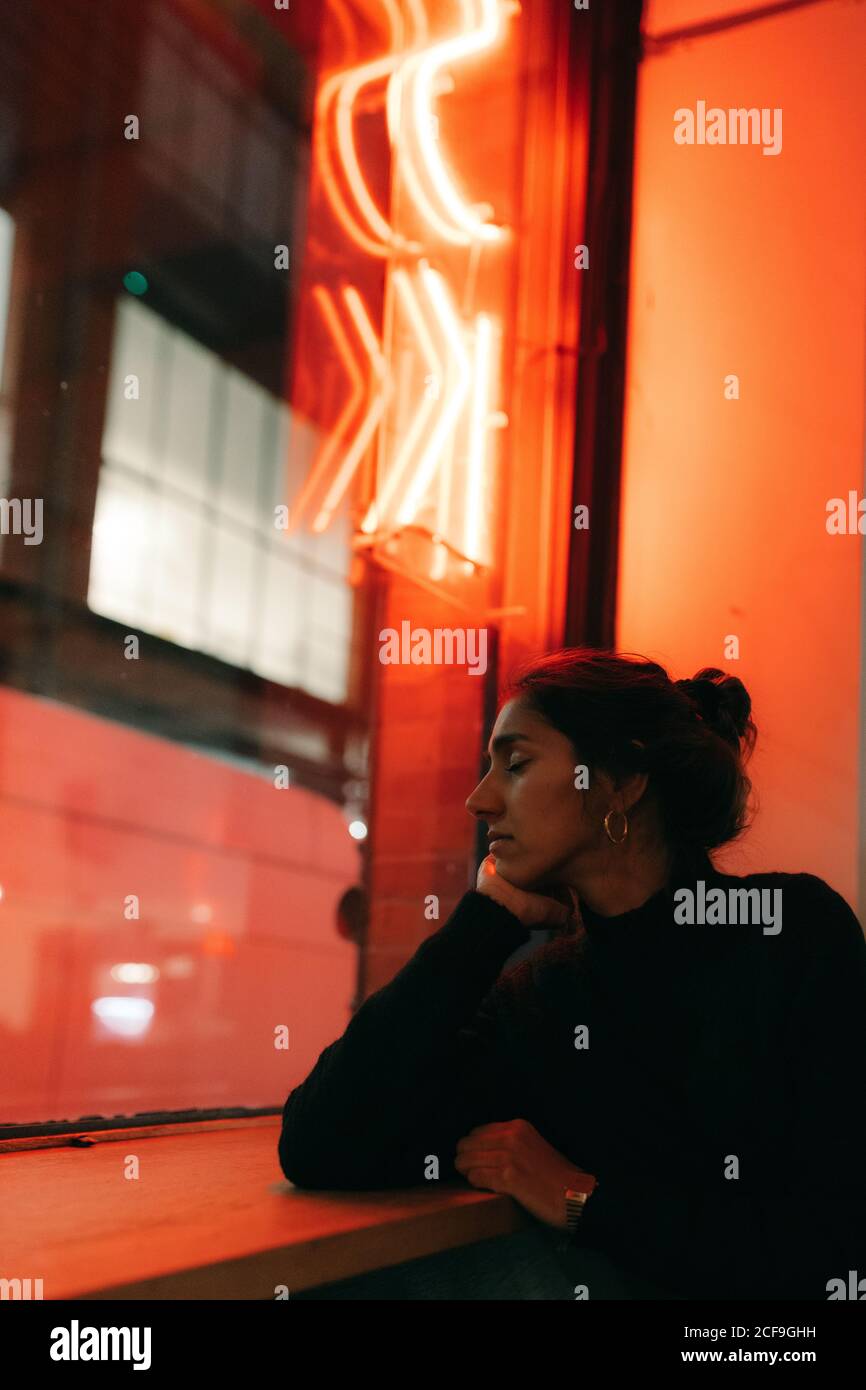 Side view of gorgeous young ethnic Woman looking out window with red ...