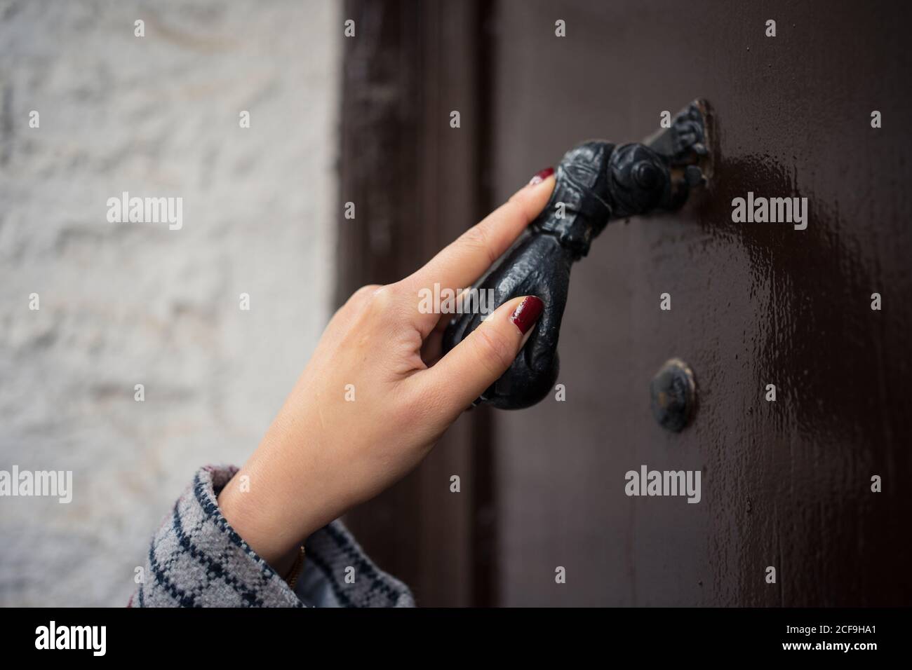 Curious female traveler in casual wear clattering in ancient door at ...