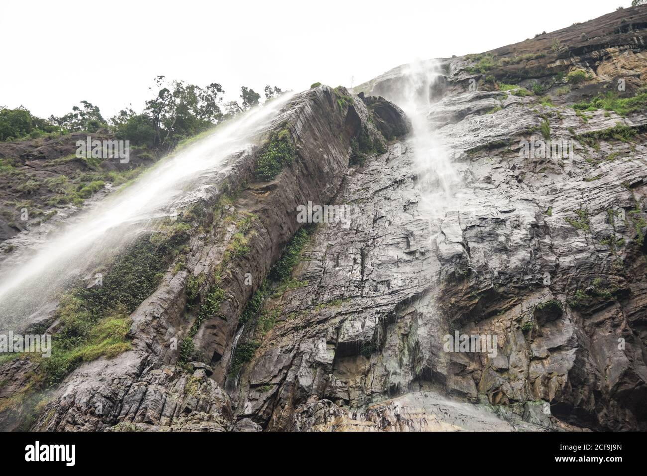 From below foamy strong waterfall streaming from rocky mountain in ...