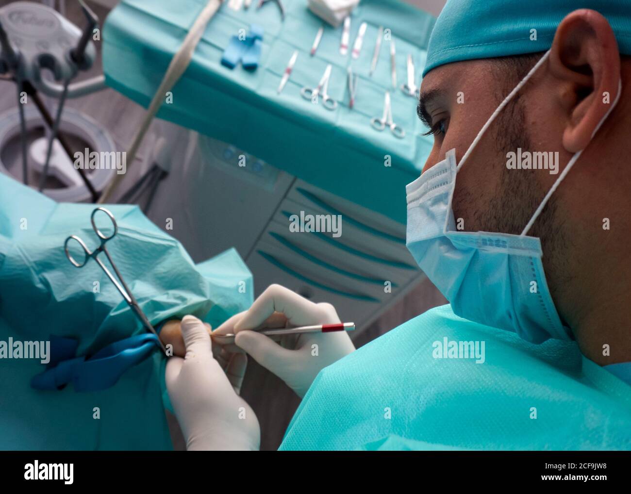 Professional male surgeon starting operation on thumb of feet in ...