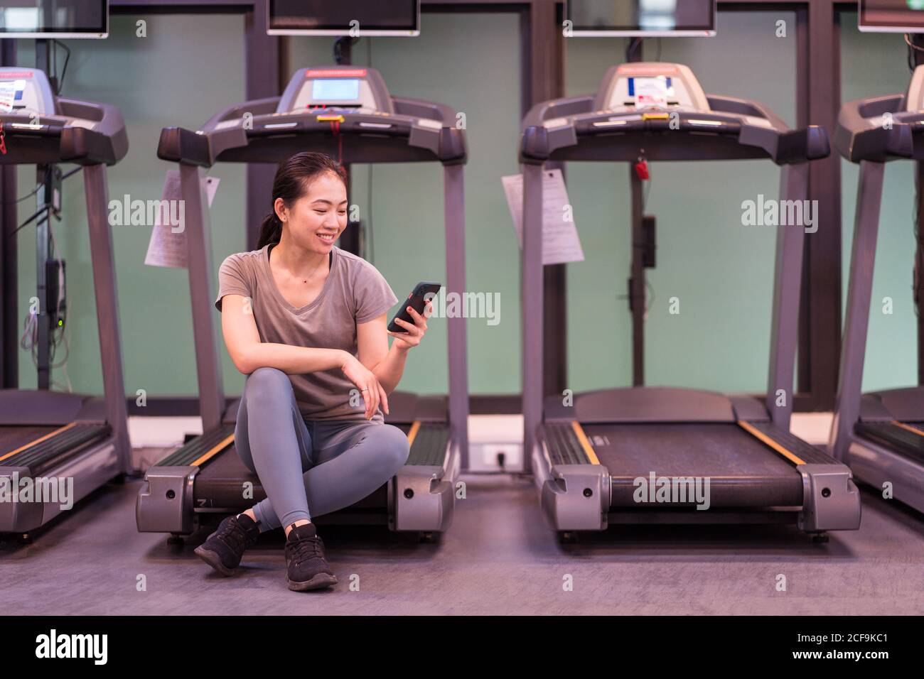 Positive young ethnic female athlete in active wear resting on ...