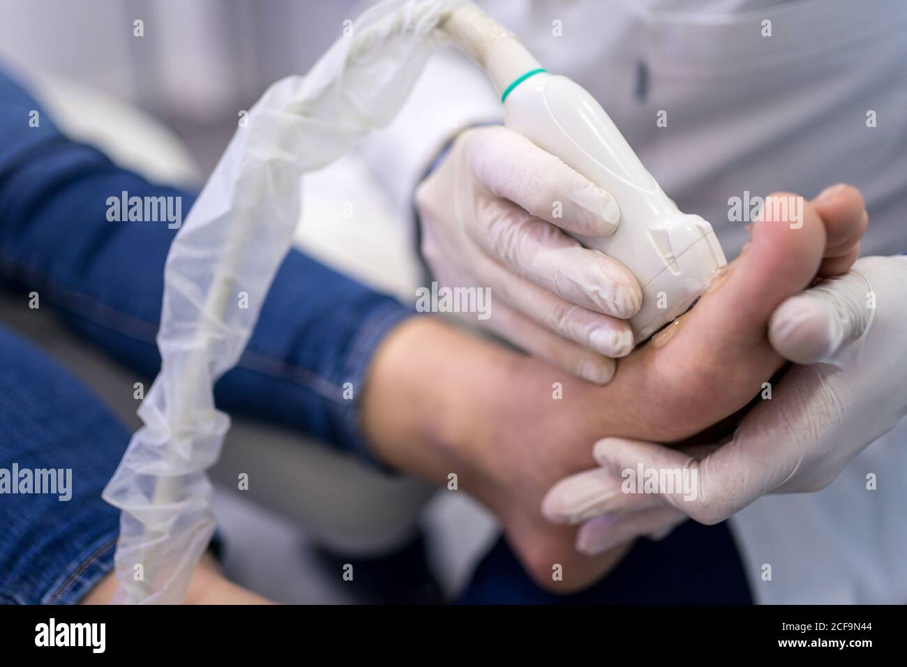 Crop podiatry doctor in protective gloves using ultrasound diagnostic ...
