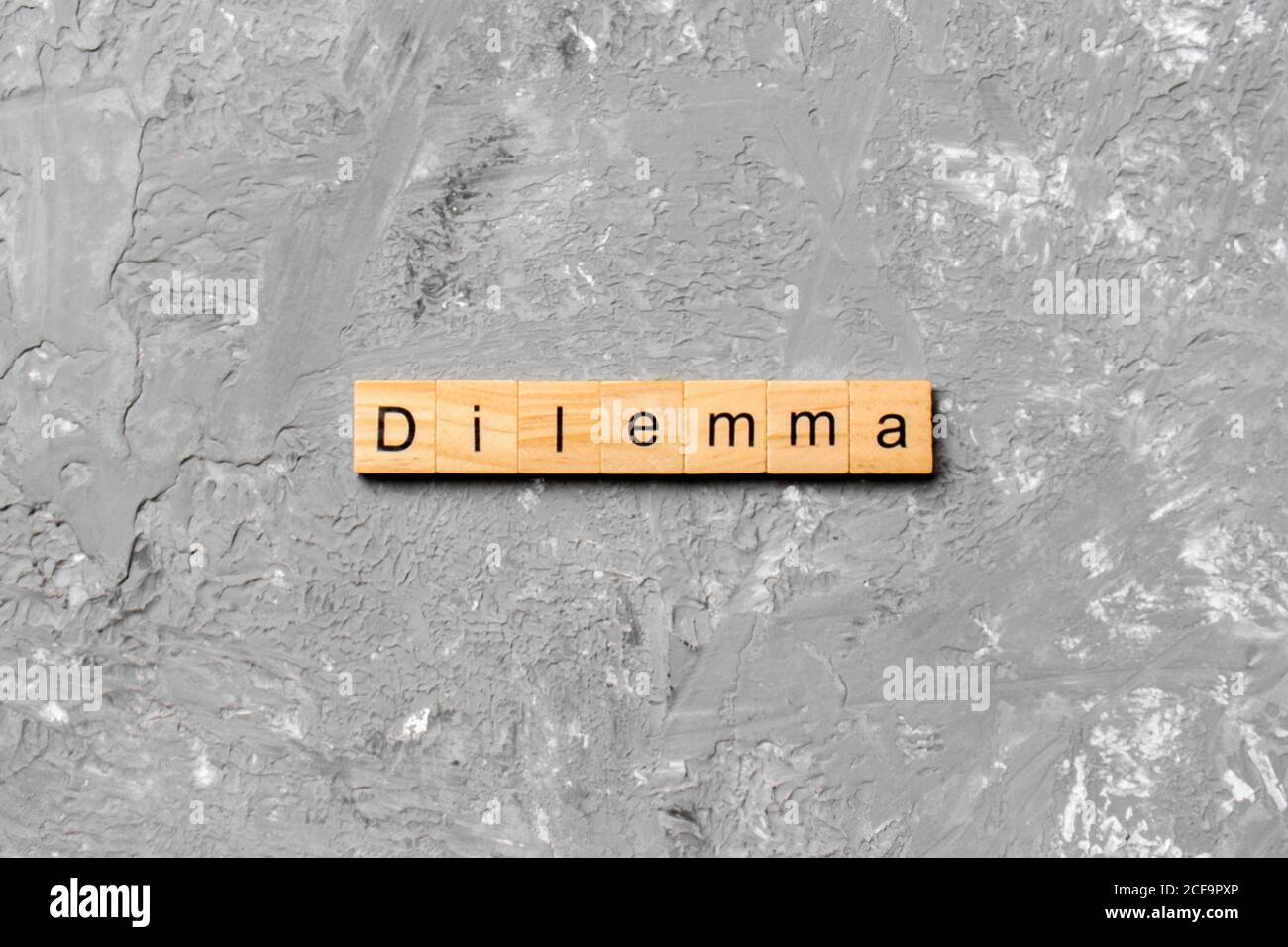 Dilemma word written on wood block. Dilemma text on cement table for ...
