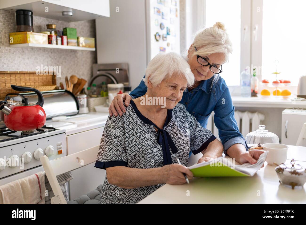 Mature woman helping elderly mother with paperwork Stock Photo - Alamy