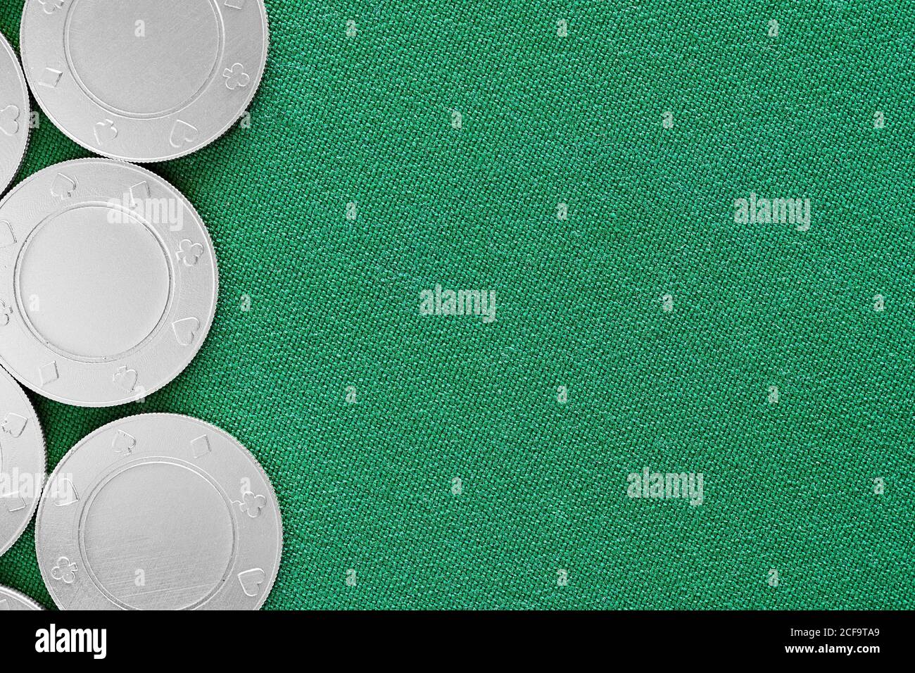 Silver gambling chips on the green poker table surface. Copy space for ...