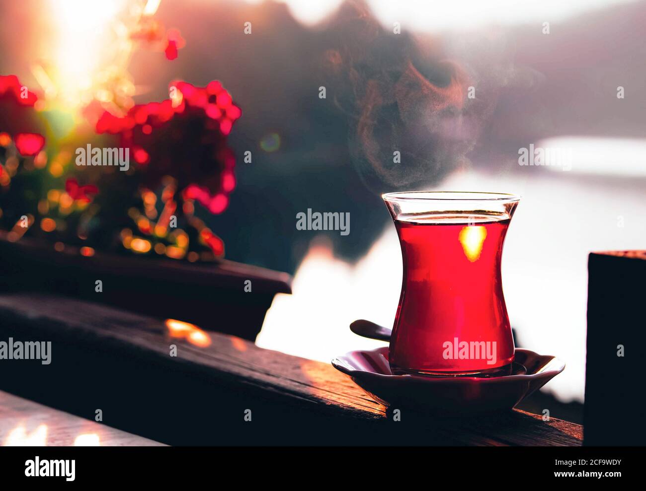 Turkish tea and beautiful sunset at the lake with red flowers ...