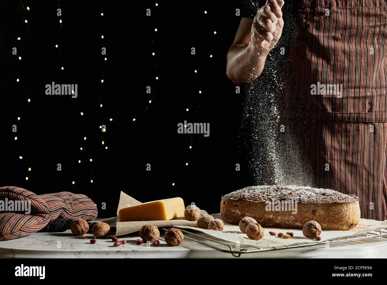 Crop anonymous male baker in apron spilling flour over baking pan with ...
