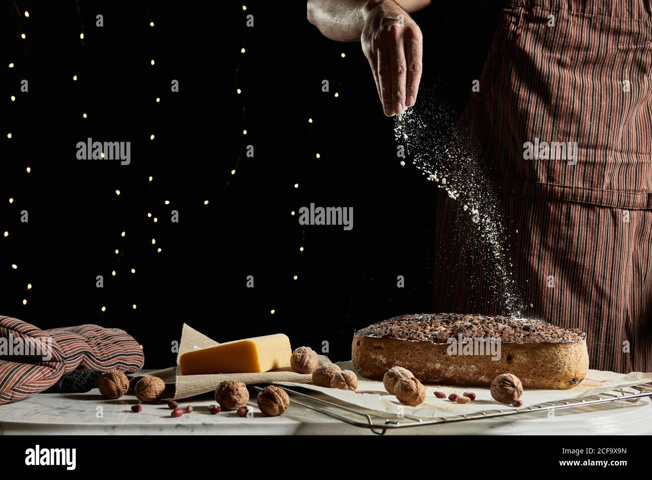 Crop anonymous male baker in apron spilling flour over baking pan with ...
