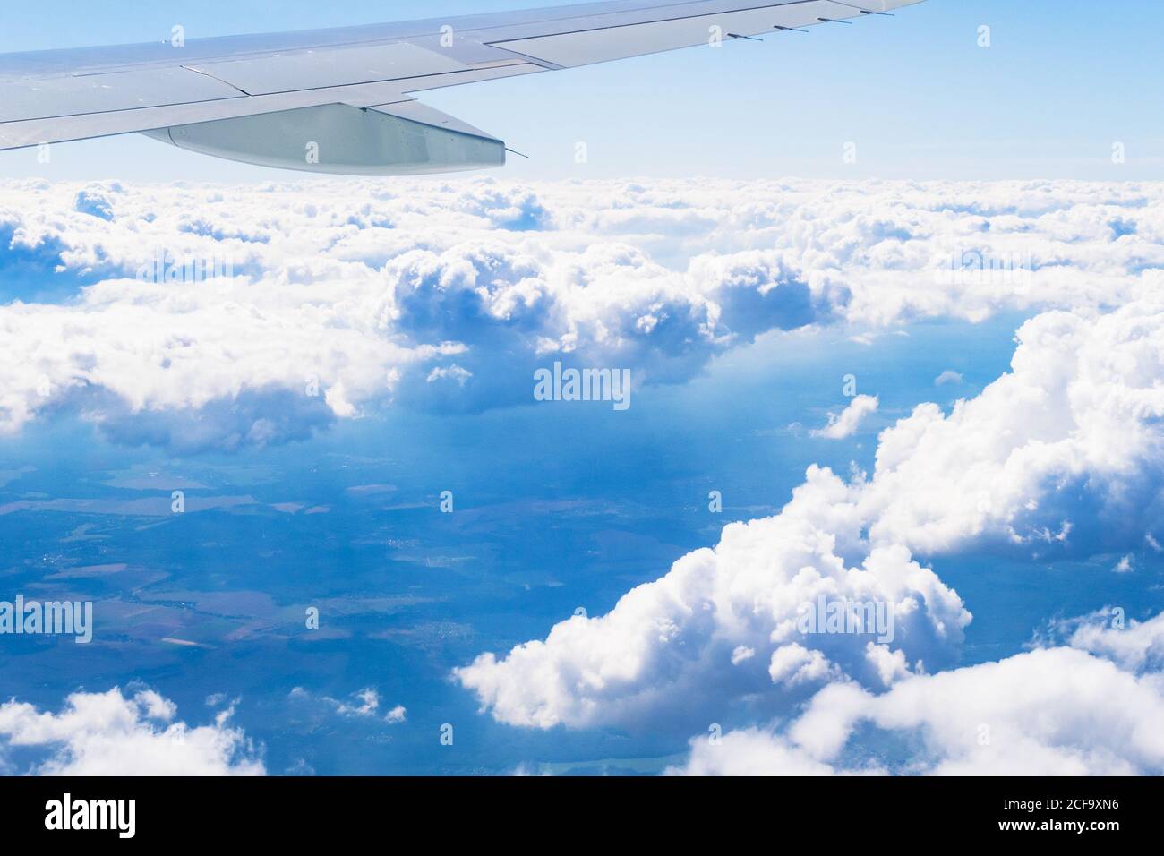 view of airplane wing, rain clouds and land during flight on summer day ...
