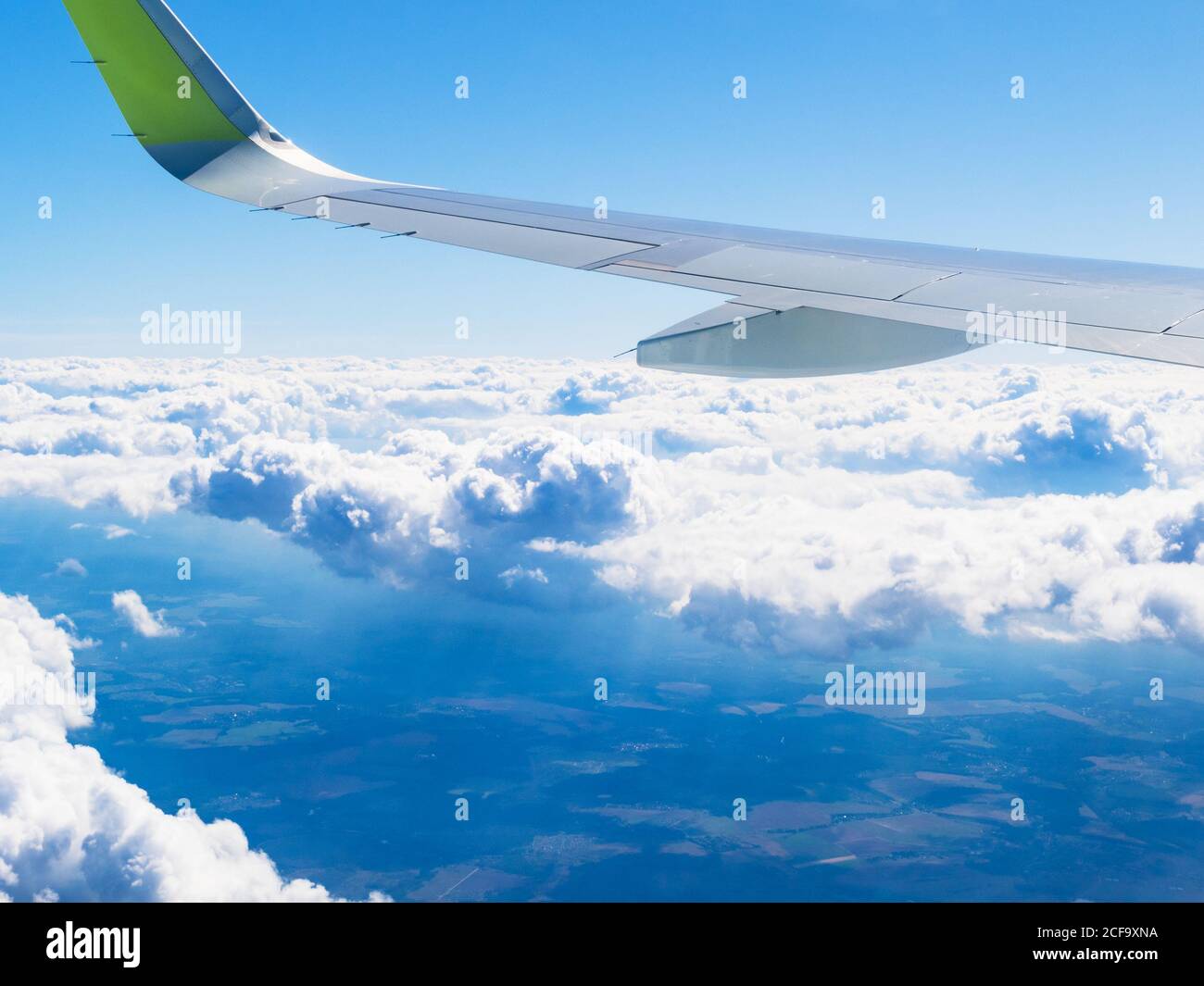 airplane wing in blue sky over rain clouds and land during flight on ...