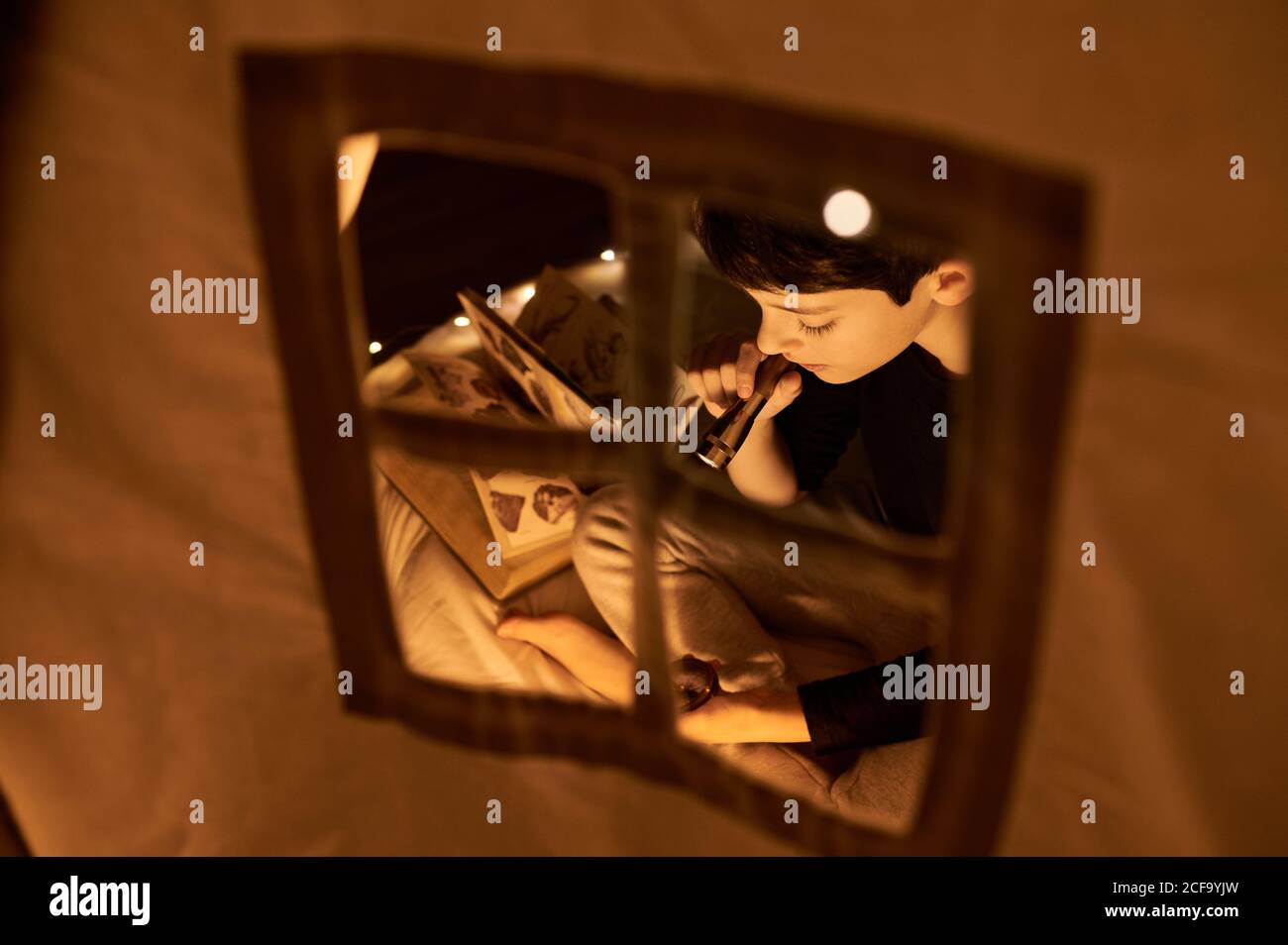 From above of focused little boy sitting with crossed legs and ...