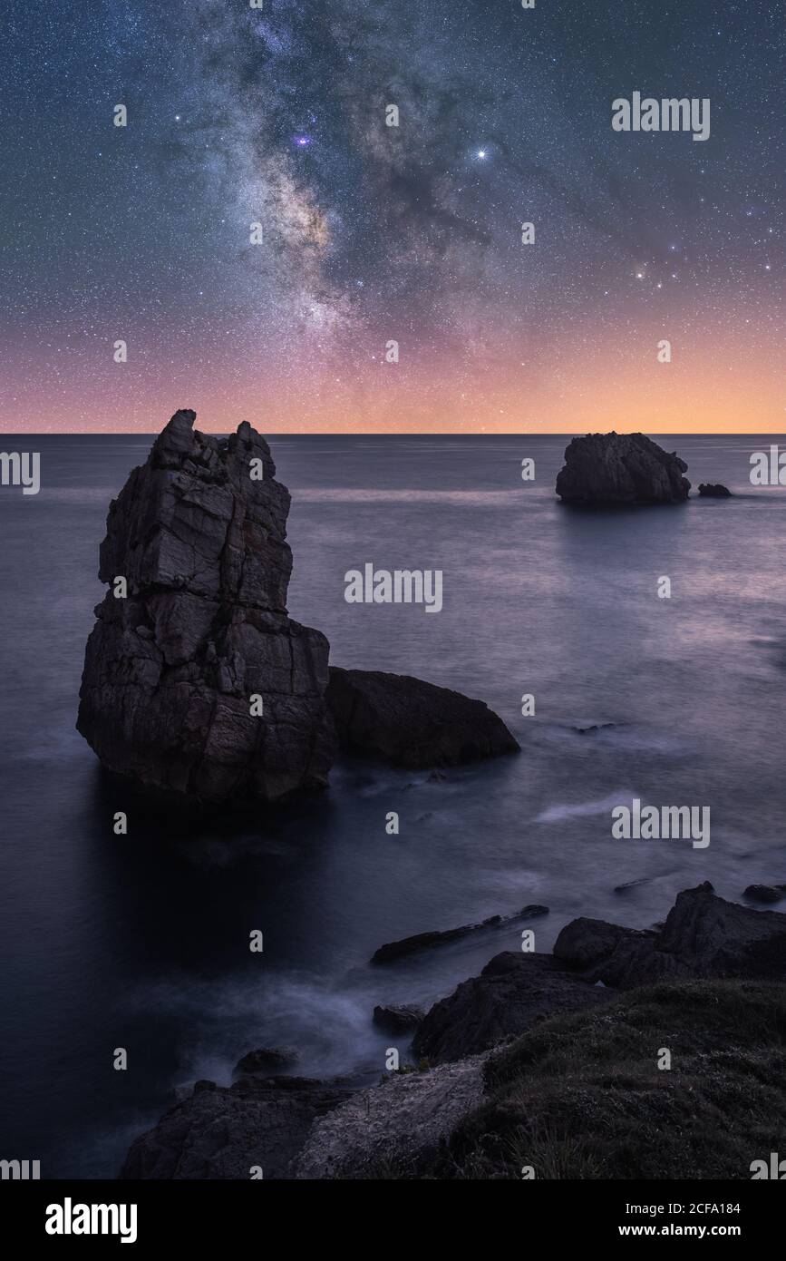 Big rough cliffs on blue calm ocean during bright evening under ...