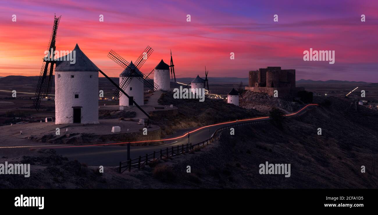 Aged windmills located on rocky cliff near medieval castle against ...