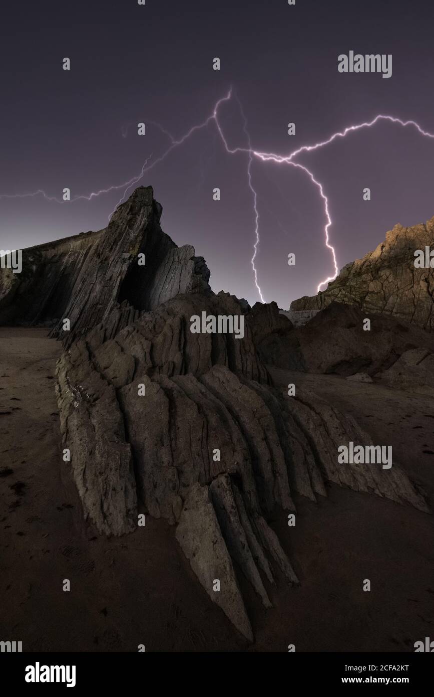 From below rough dramatic landscape of rocky cliff under dark stormy ...