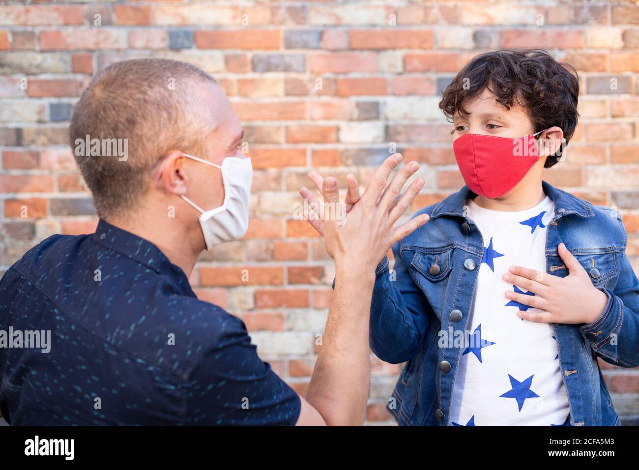 Father and son greeting each other on the street. They are wearing a ...