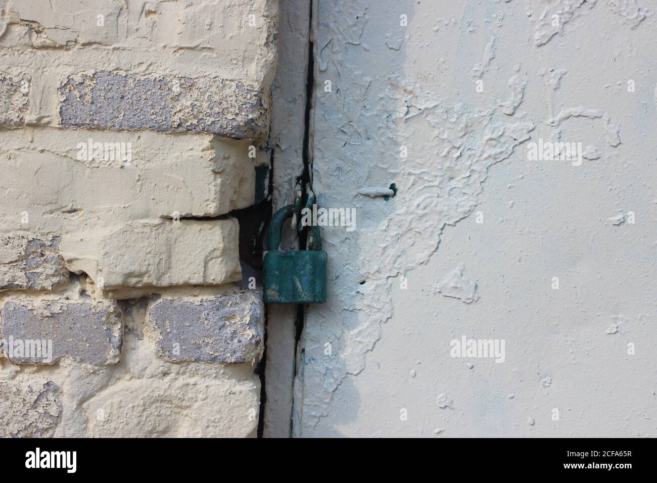 Security padlock of heavy metal door painted into white and white brick ...