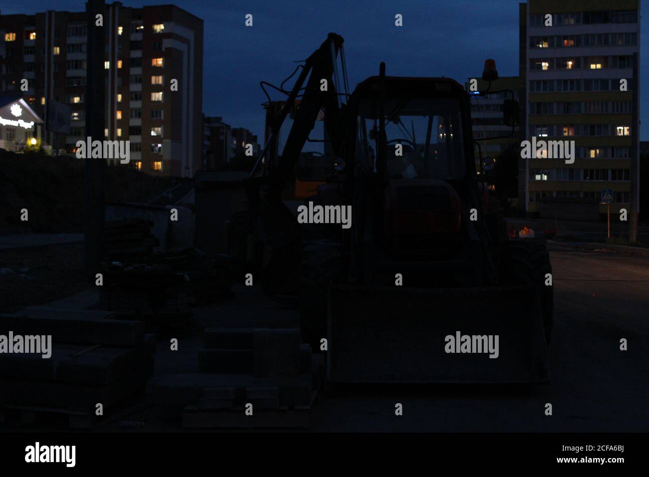 tractor in the city on construction repair work in the city at night in ...