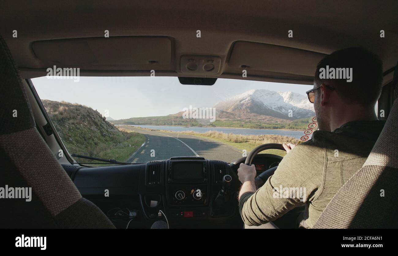 Back view of faceless male driver looking at road while riding vehicle ...