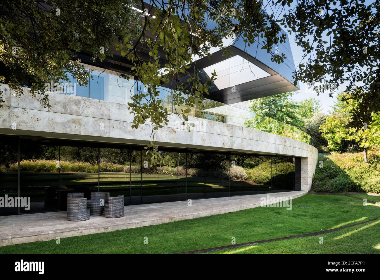Facade of huge contemporary building in futuristic style with lush lawn ...